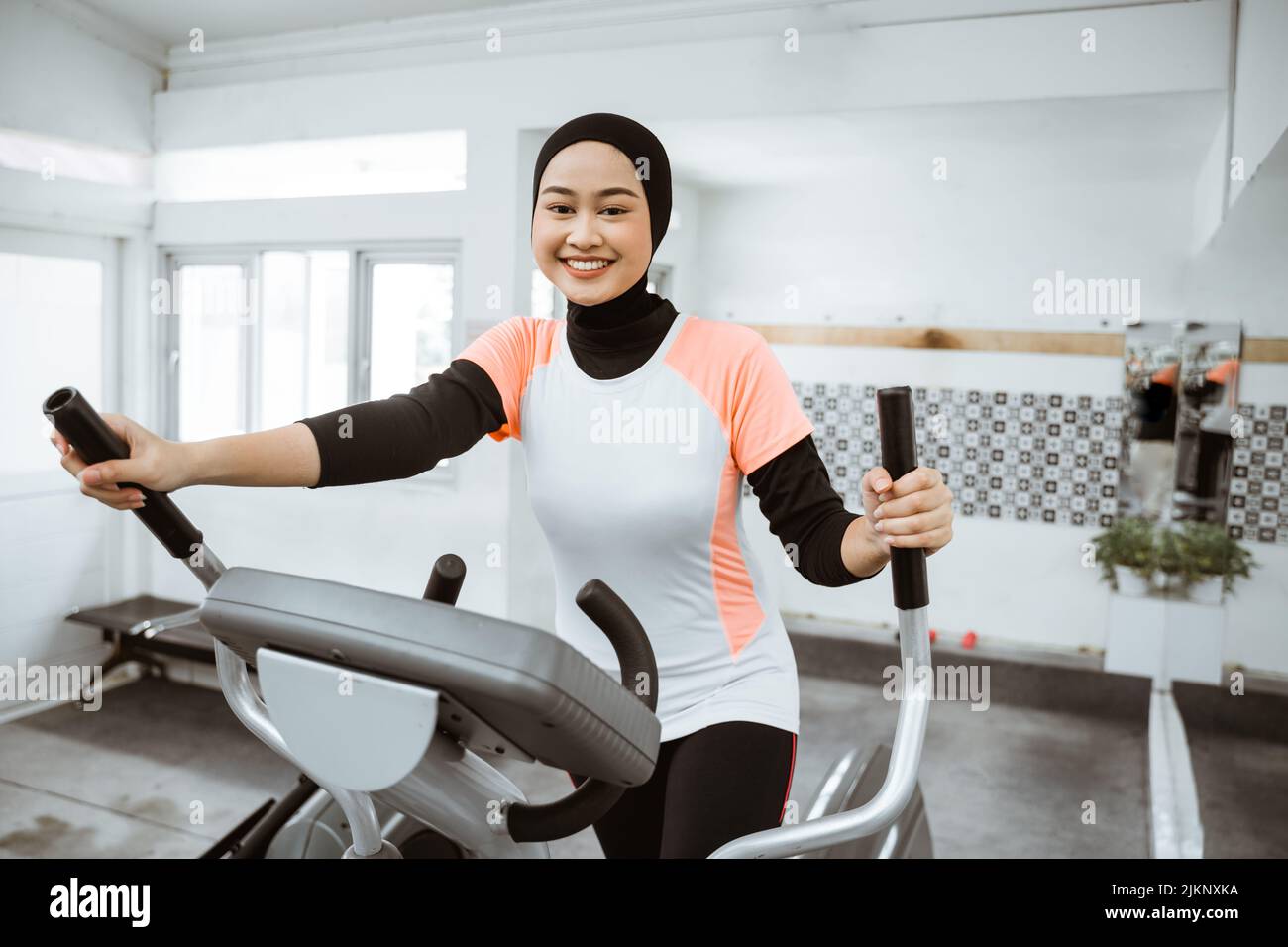 muslim women at the gym doing exercises on static elliptical cycle ...