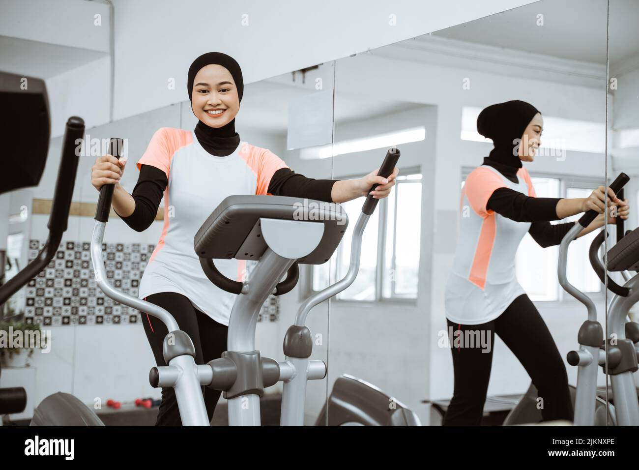 muslim women at the gym doing exercises on static elliptical cycle ...