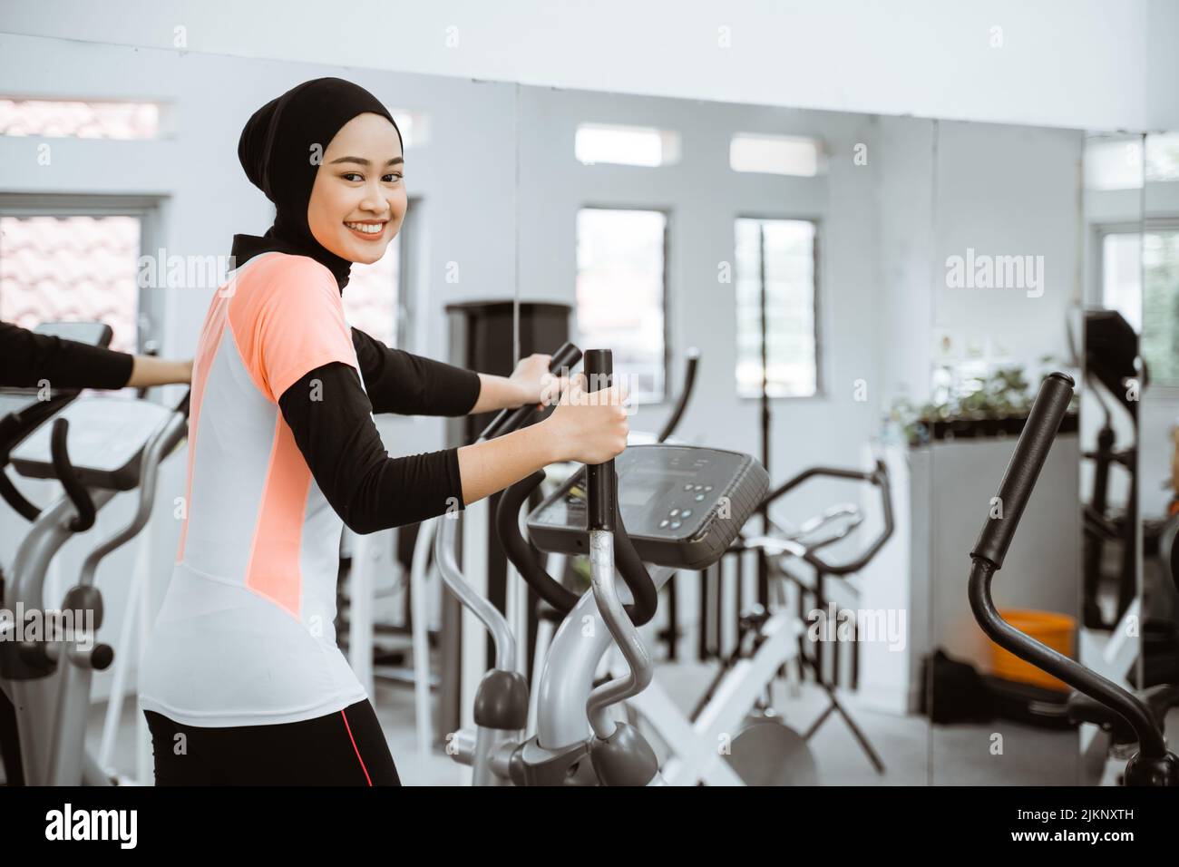 muslim women at the gym doing exercises on static elliptical cycle ...