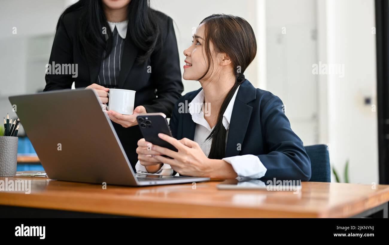 A pretty young Asian businesswoman or female trainee employee talking ...