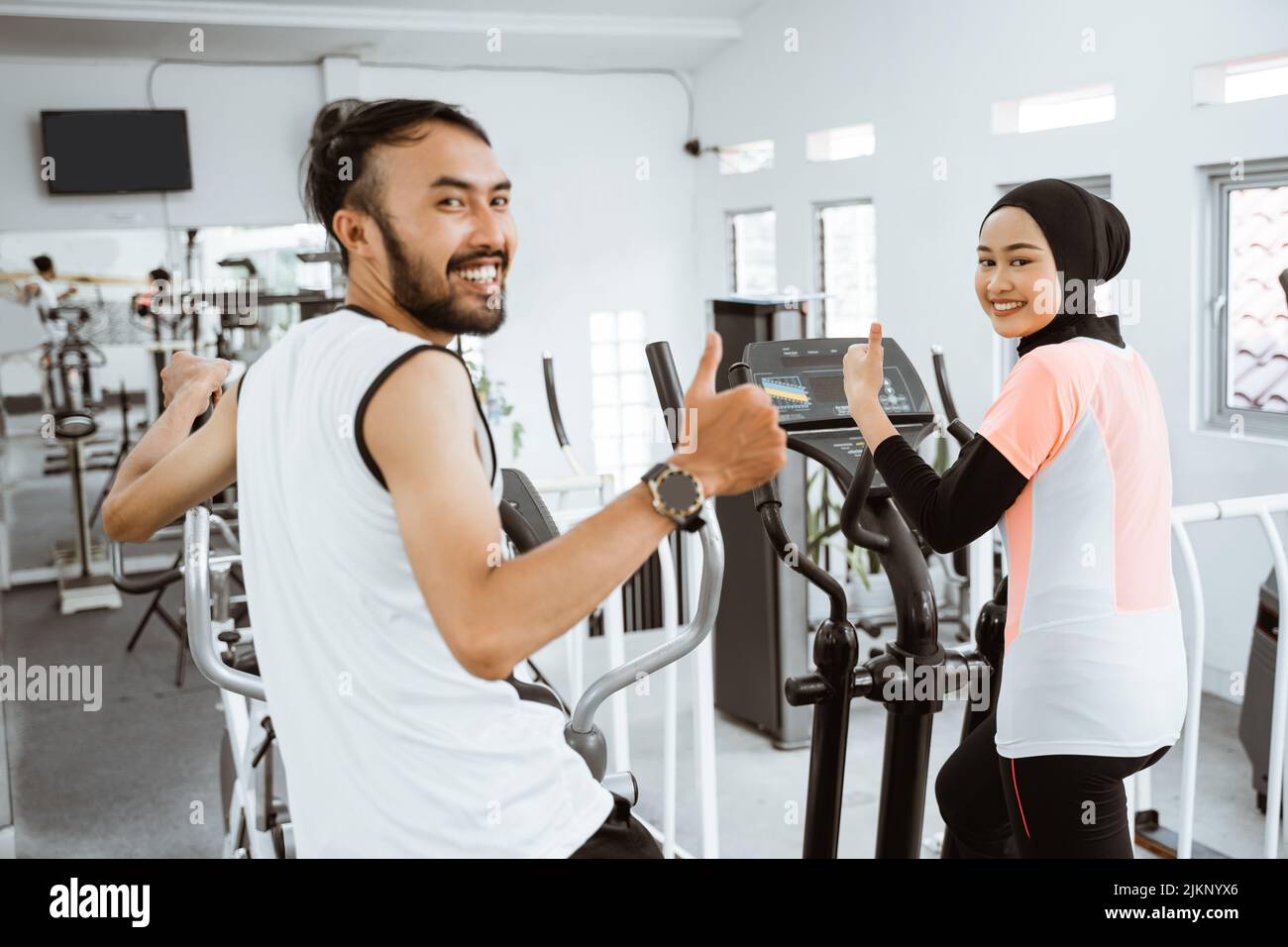 muslim couple using elliptical cycle machine for exercising together ...