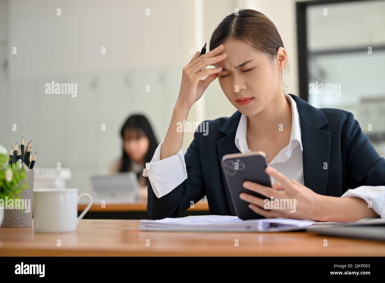 Unhappy young Asian businesswoman or female office worker at her office ...