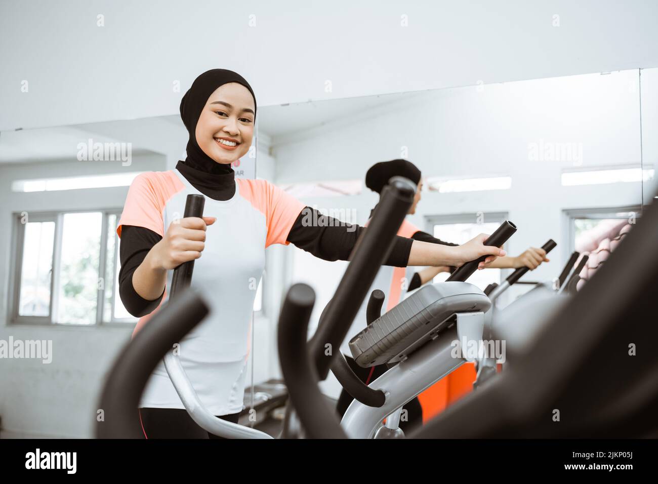 muslim women at the gym doing exercises on static elliptical cycle ...
