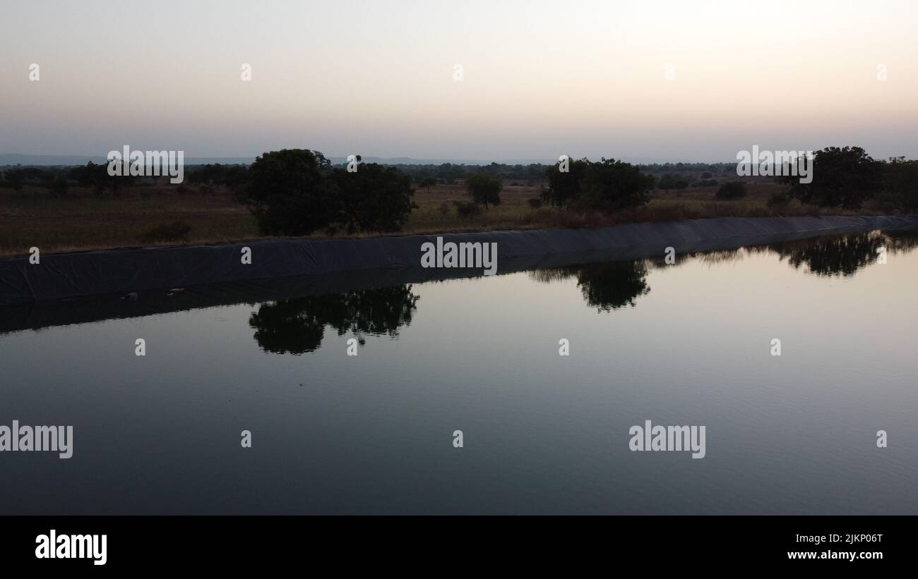 A beautiful scene of land with trees reflecting on Wakadi water with ...