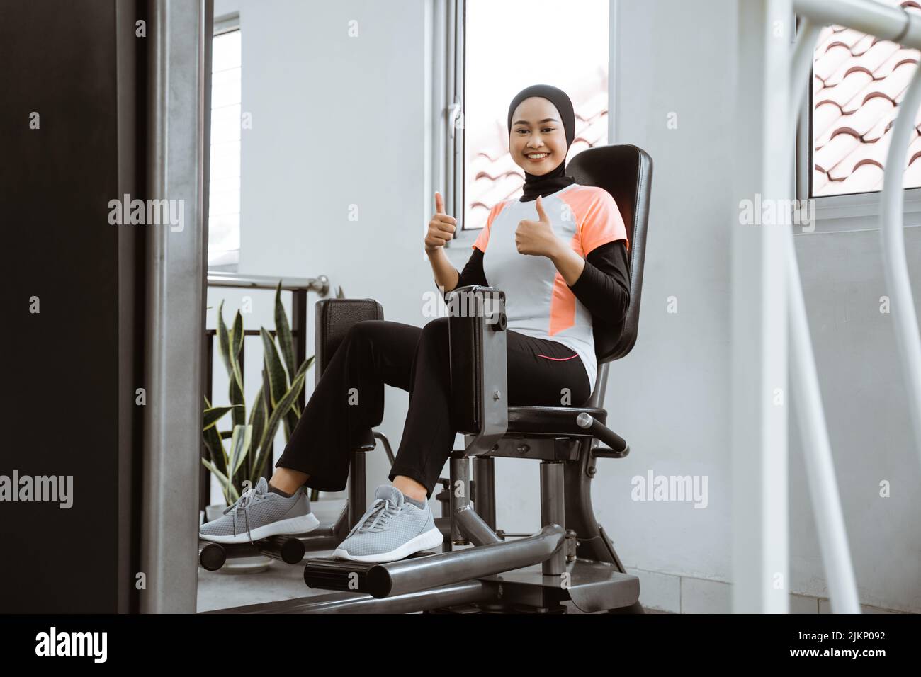asian woman working on her lower body using leg machine Stock Photo - Alamy