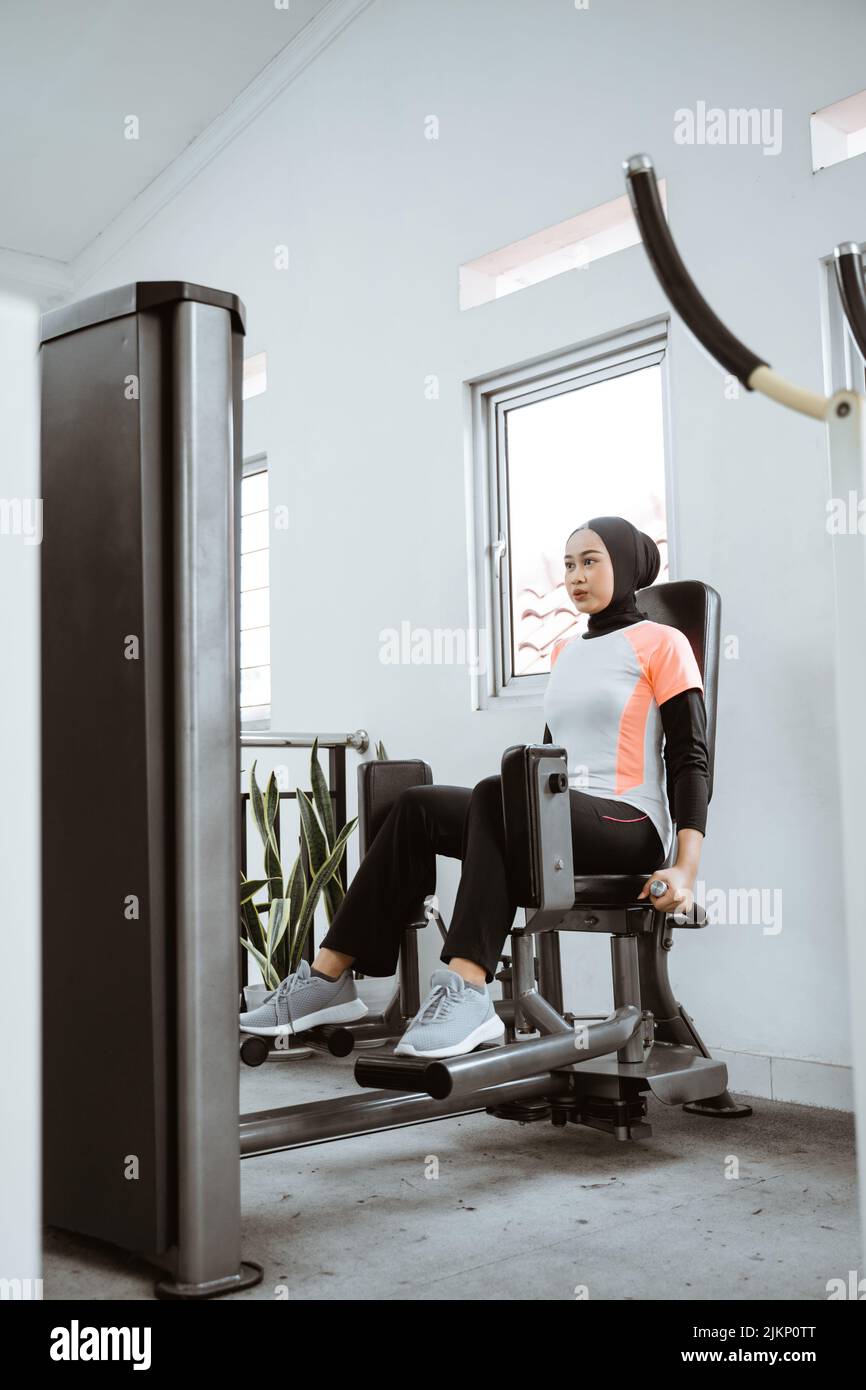 asian woman working on her lower body using leg machine Stock Photo - Alamy