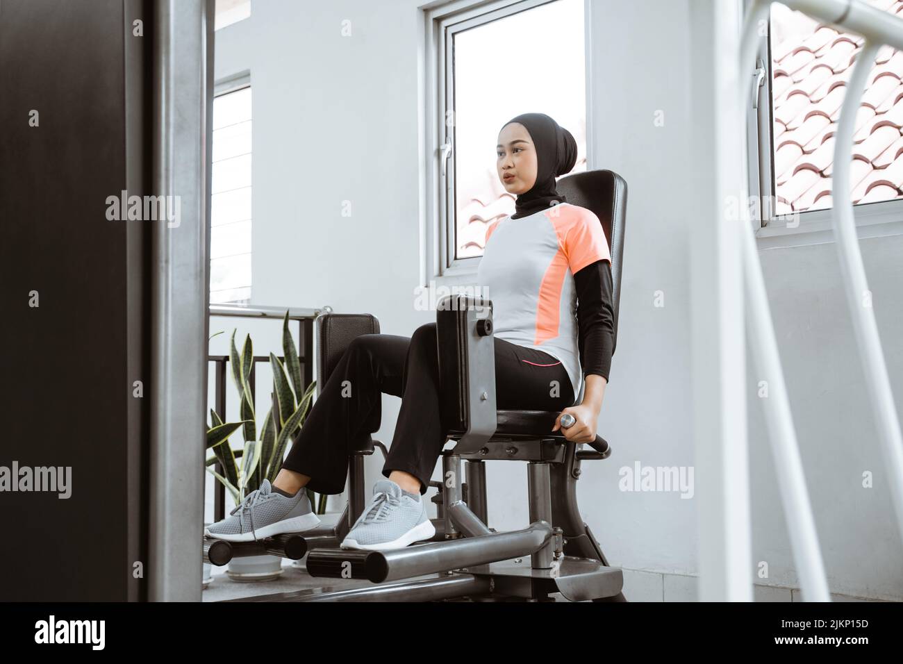 asian woman working on her lower body using leg machine Stock Photo - Alamy