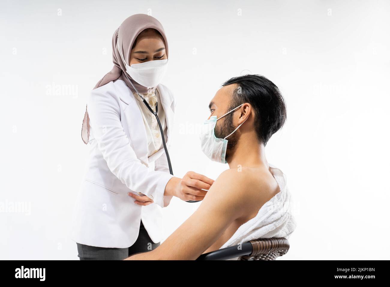 Masked doctor using a stethoscope examining prospective pilgrims Stock ...