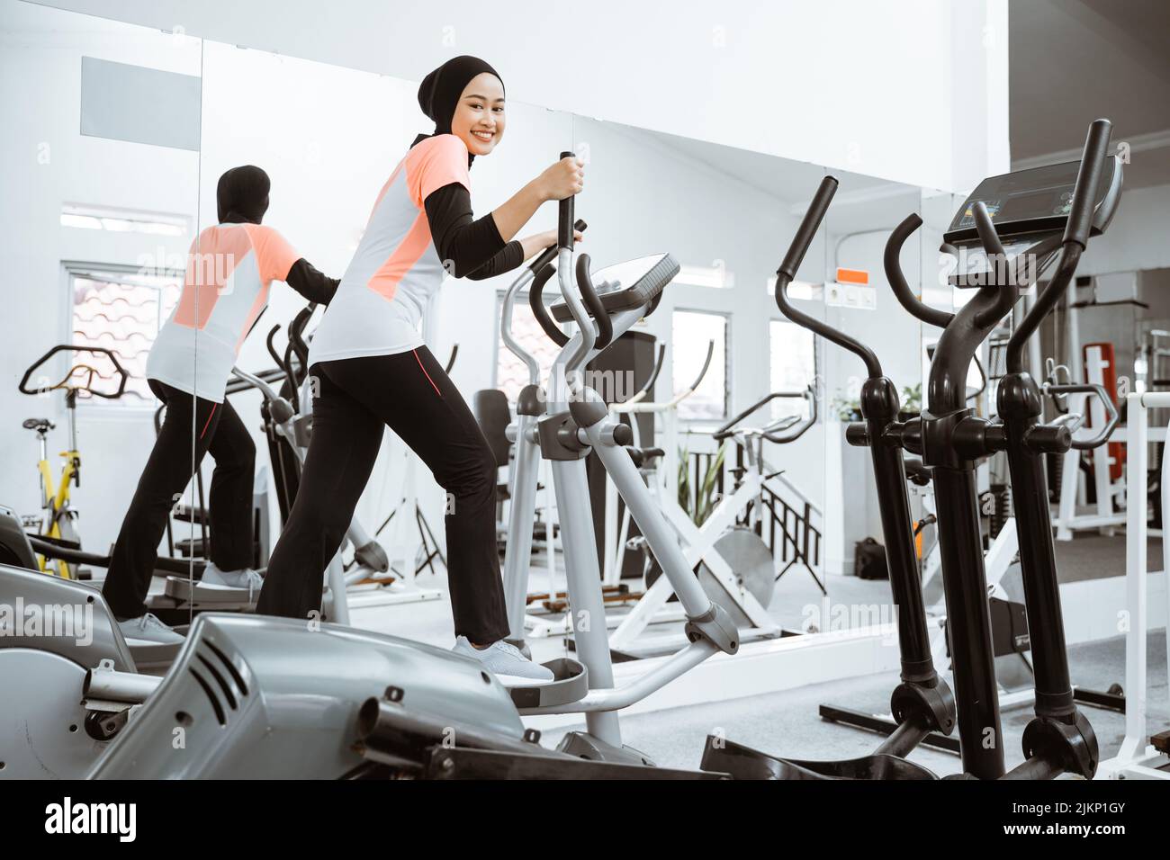 muslim women at the gym doing exercises on static elliptical cycle ...