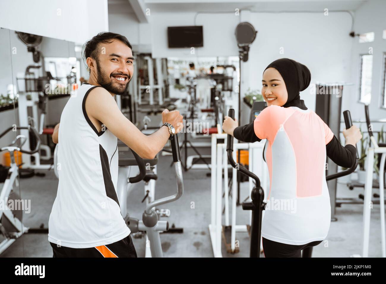 muslim couple using elliptical cycle machine for exercising together ...