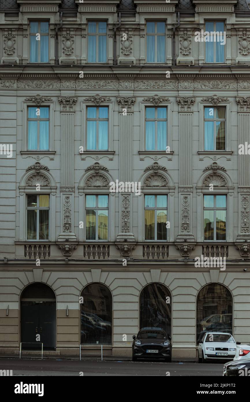 A view of engraved architectural building facade in front of cars in ...