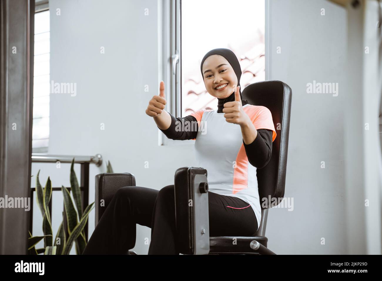 asian woman working on her lower body using leg machine Stock Photo - Alamy