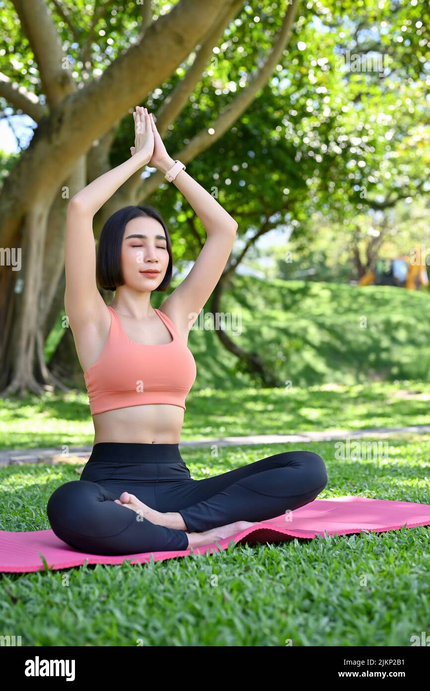 Calm Asian female in sportswear practicing yoga, breathing deeply ...