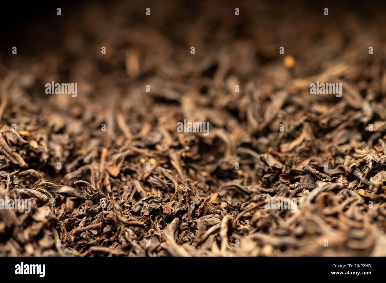 Large-leaved black tea in bulk on the table. Close-up of the surface ...
