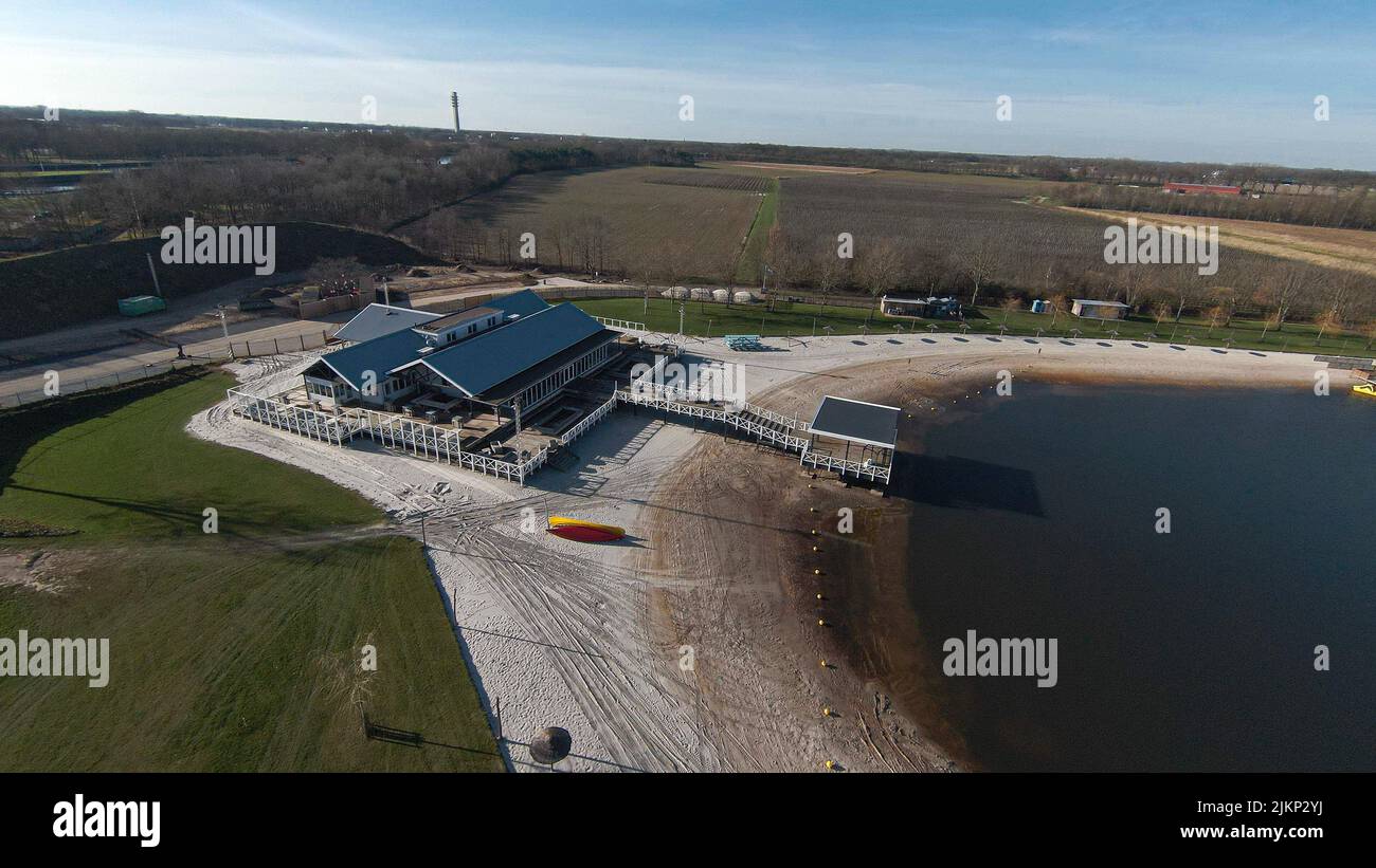 An aerial view of a building next to a lake in a countryside under a ...
