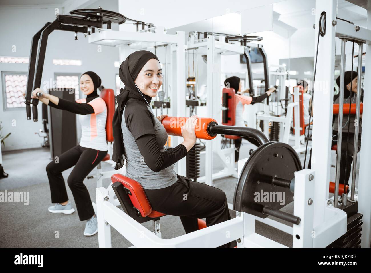 woman using chest press machine at the gym with friend Stock Photo - Alamy