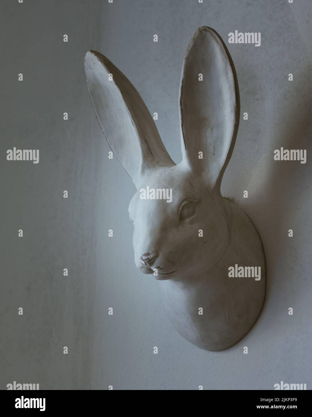A vertical shot of a sculpture of a rabbit head on the white wall Stock ...