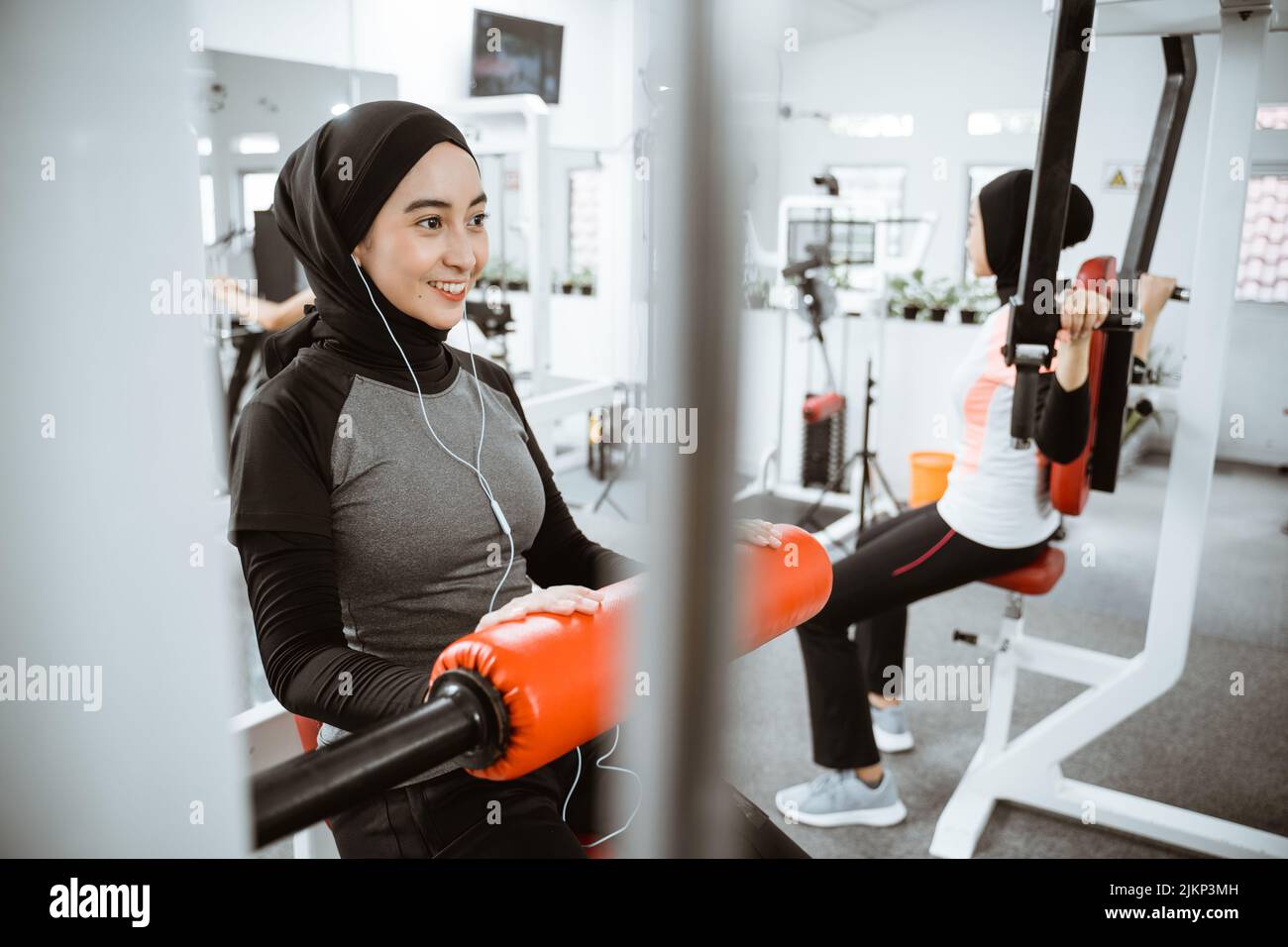 asian woman working on her lower body using leg machine Stock Photo - Alamy