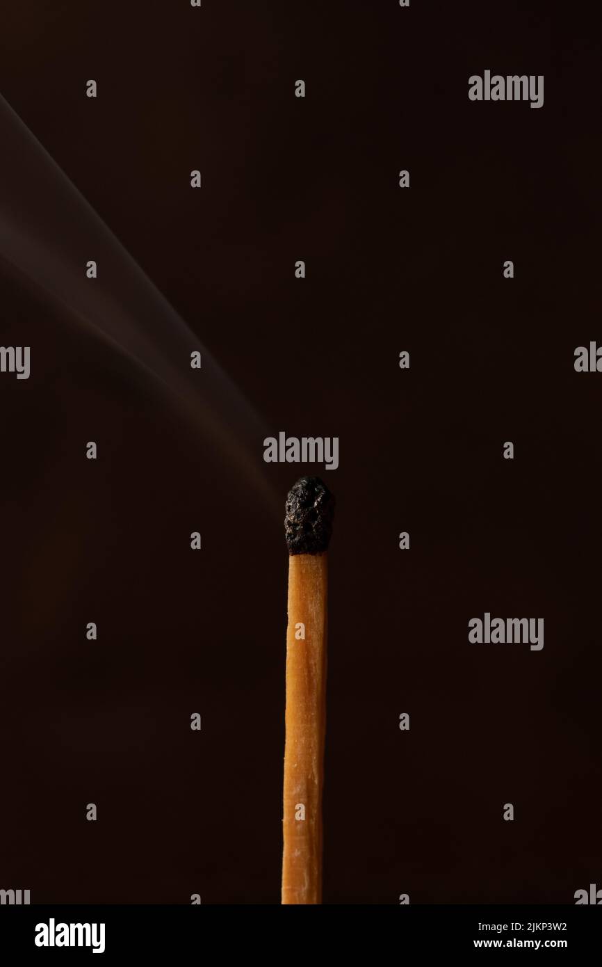 A vertical shot of a burnt wooden matchstick isolated on a black ...