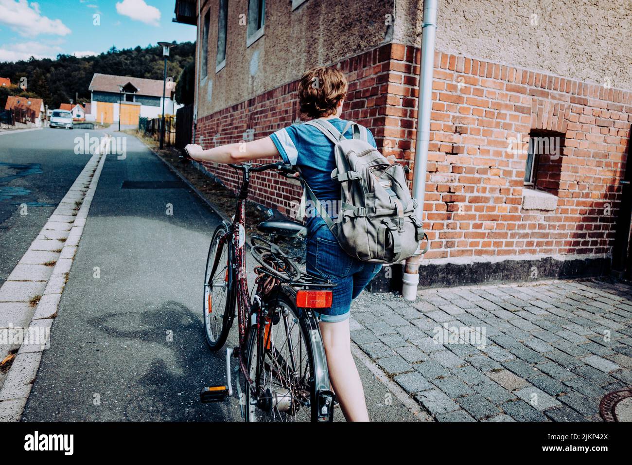 A cyclist taking his bicycle through a narrow path surrounded by old ...