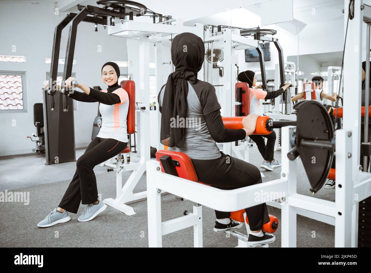 woman using chest press machine at the gym with friend Stock Photo - Alamy