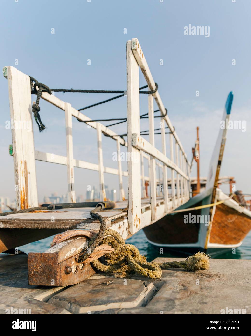 A closeup shot of a white wooden pier from a dock to a wooden boat in ...