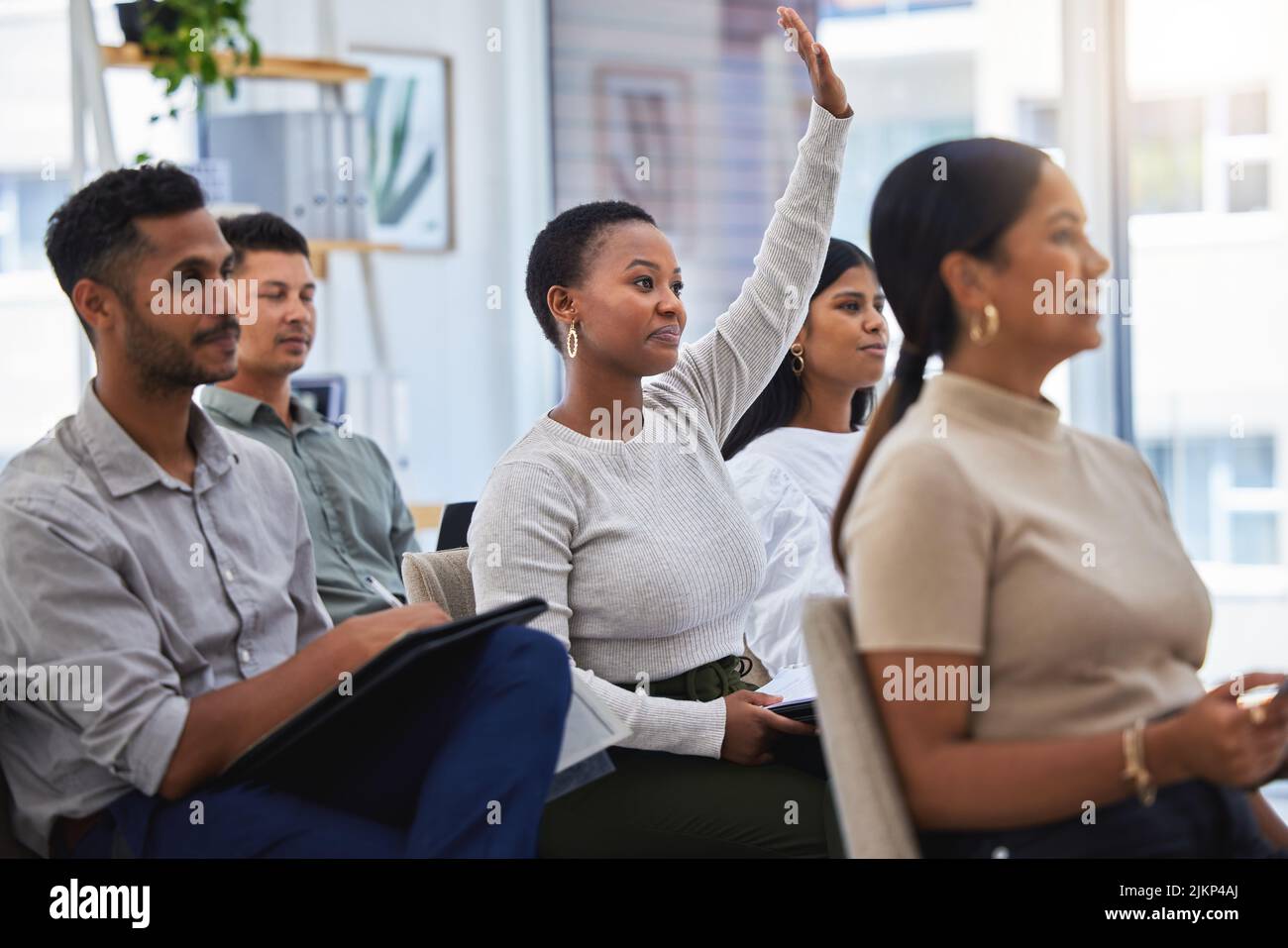 Who wants a promotion. a young woman raising her hand at work in a ...
