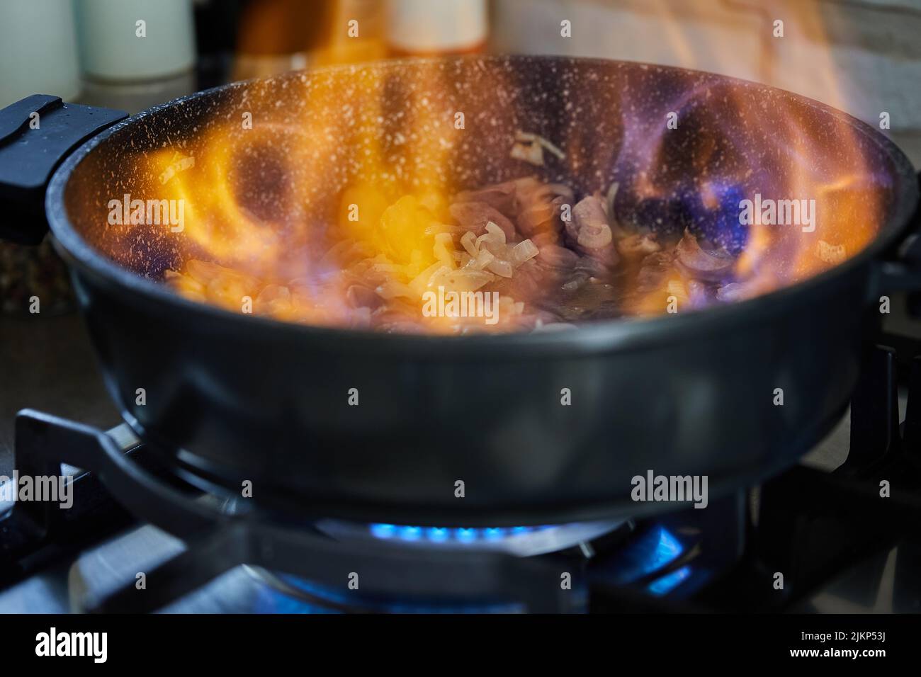Beef meat fried with onions in frying pan, flambe on gas stove Stock ...