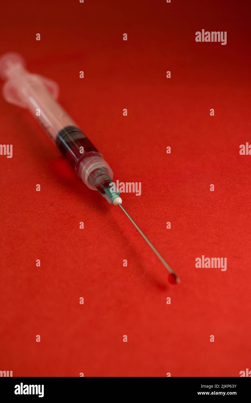 A concept of blood donation - a vertical shot of a syringe with blood ...