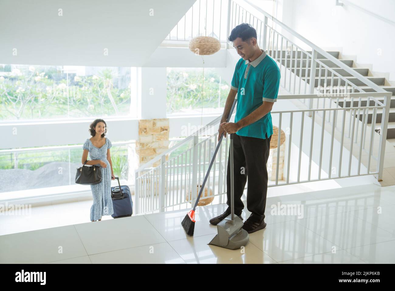 Janitor sweeps as female guests climbing stairs in hotel Stock Photo ...