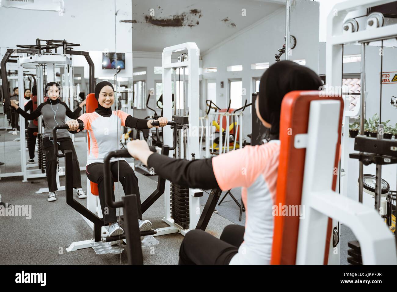 woman using chest press machine at the gym with friend Stock Photo - Alamy