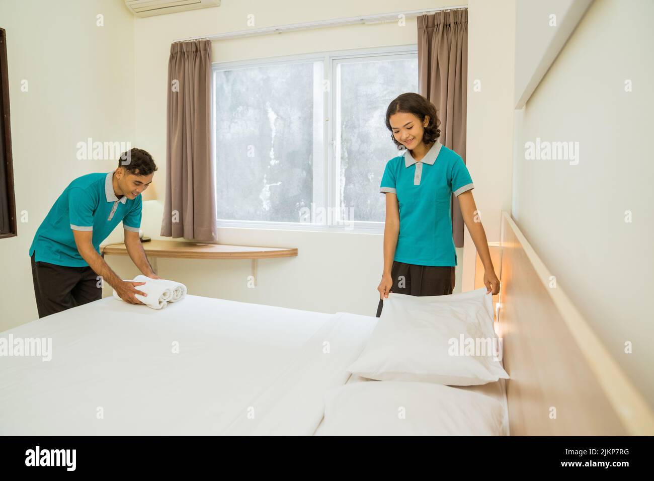 two asian janitors wearing turquoise uniforms making bed Stock Photo ...