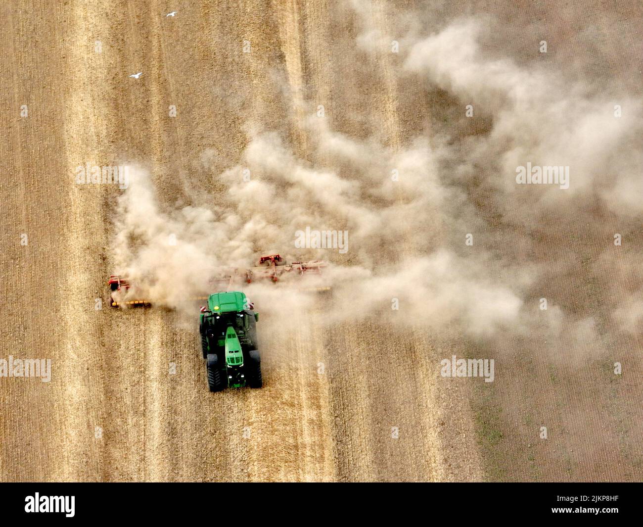 A farmer in his John Deere tractor, with caterpillar tracks, kicks up ...