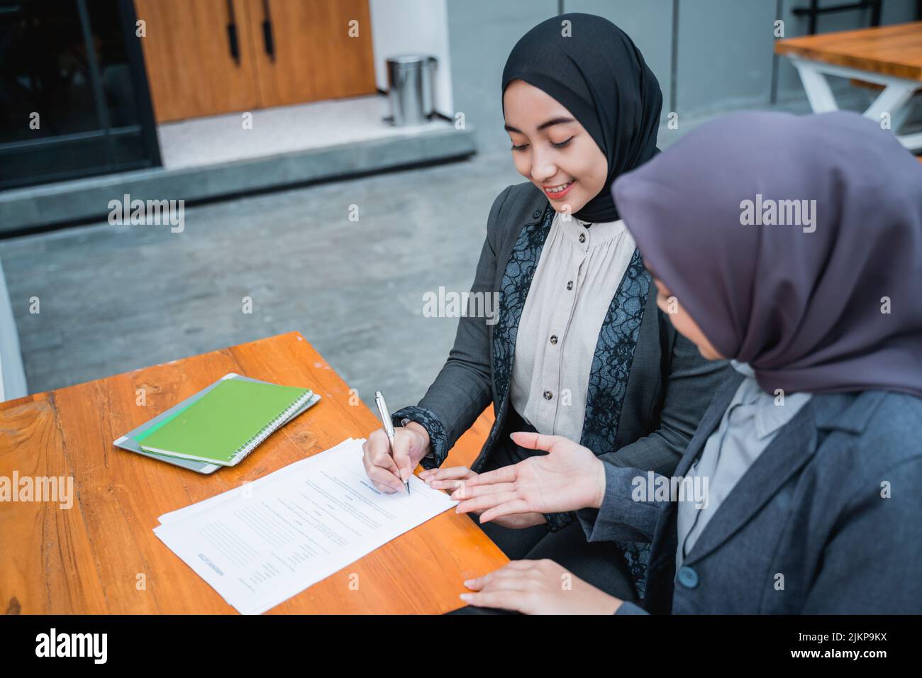 businesswoman signing an agreement letter during meeting with partner ...