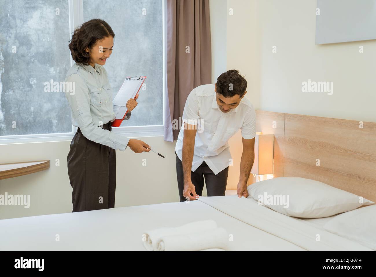 Housekeeping manager carrying clipboard notes while supervising maid ...