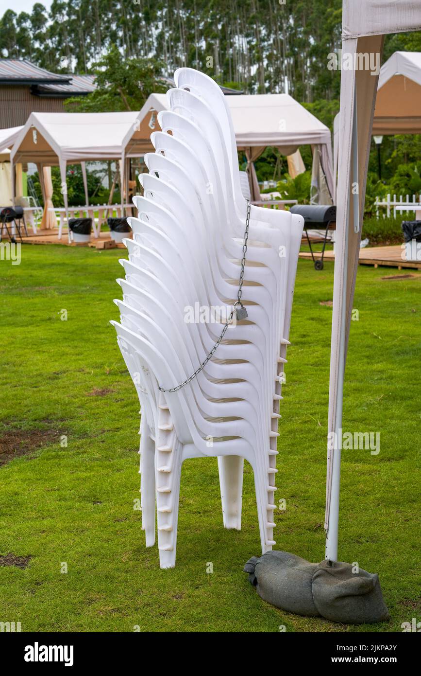 Stack of white plastic chairs in an outdoor party Stock Photo - Alamy