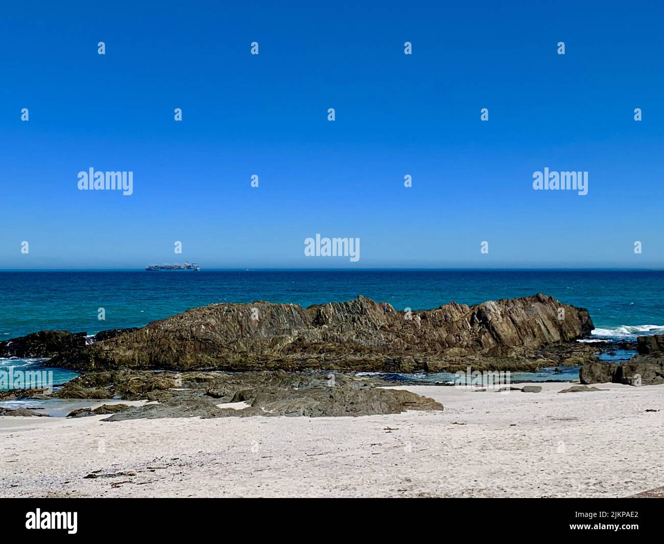 A scenic view of rock formations on the beach in the blue sky ...