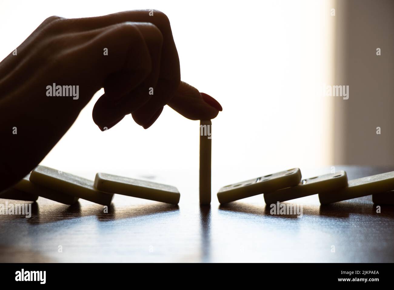 Woman's hand and dominoes on the table in the dark, domino effect ...