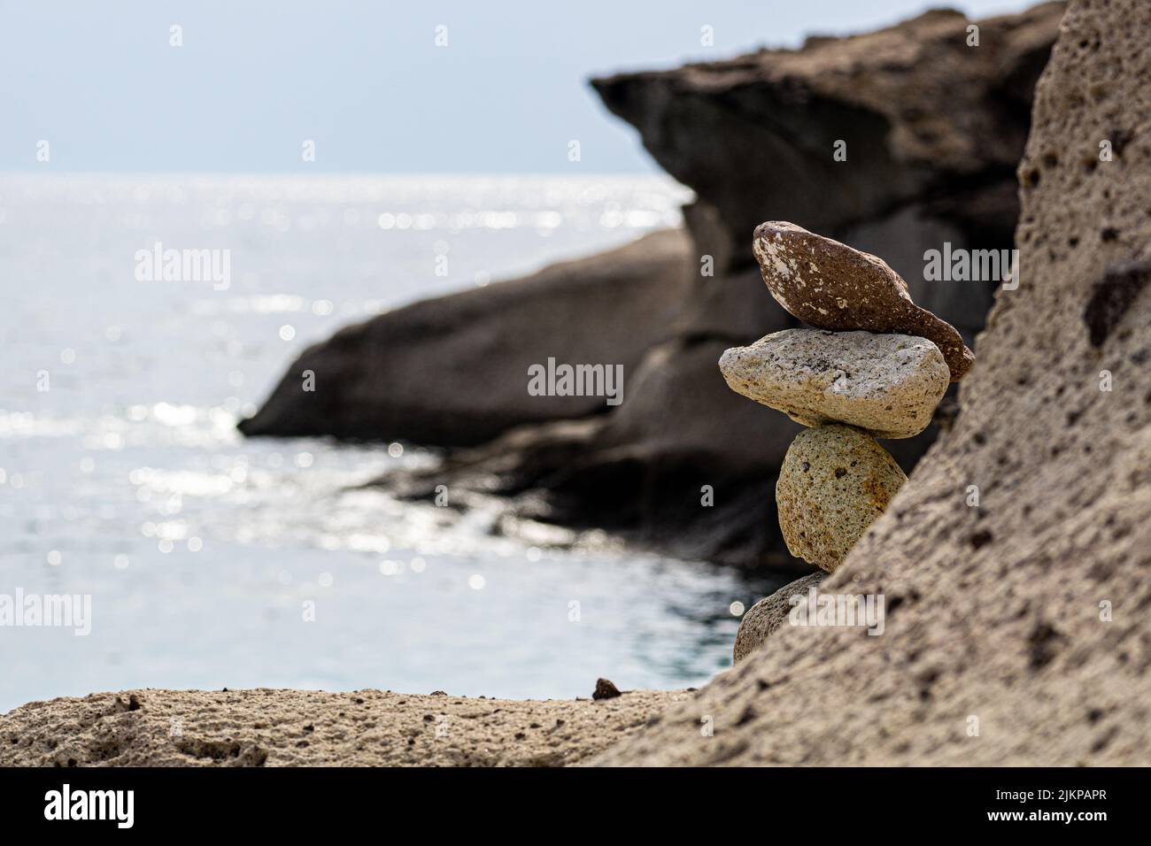 A soft focus of a stack of stones behind a rock at a seashore in ...