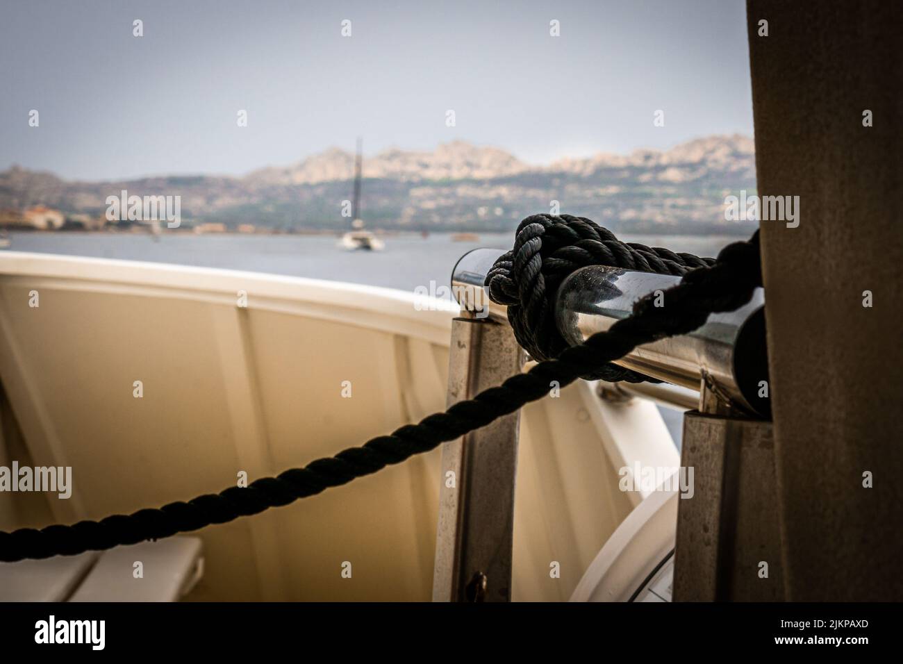 A closeup of a black rope fastened to a boat metal bar on a boat Stock ...