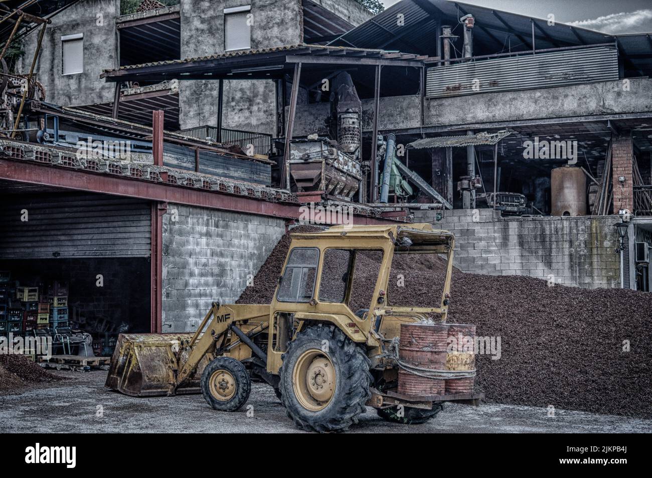 Old yellow tractor with shovel in the old factory. Massey Ferguson ...