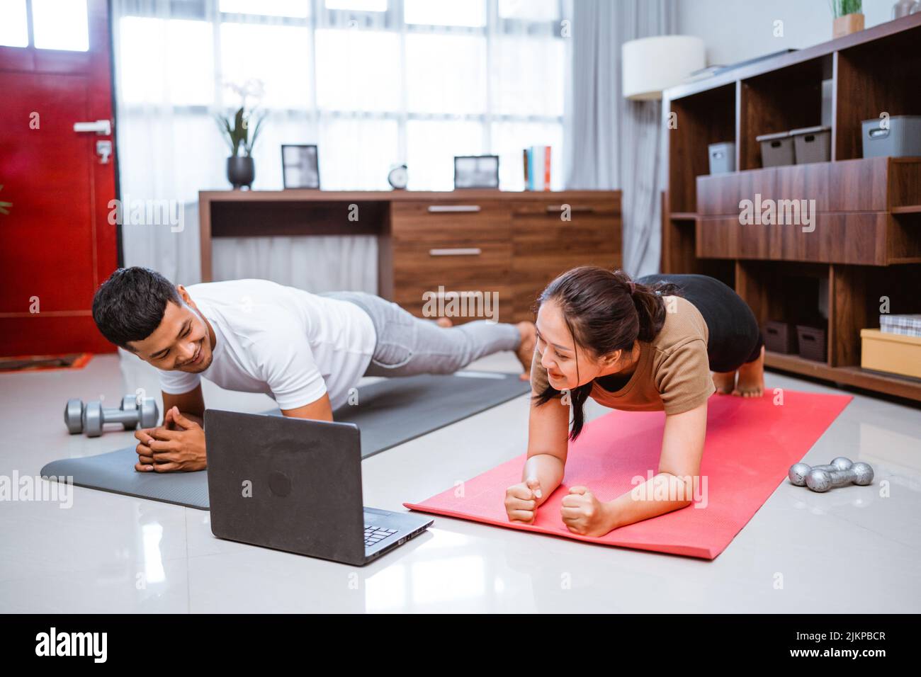 Asian fitness couple planking and looking at online video tutorial Stock Photo - Alamy