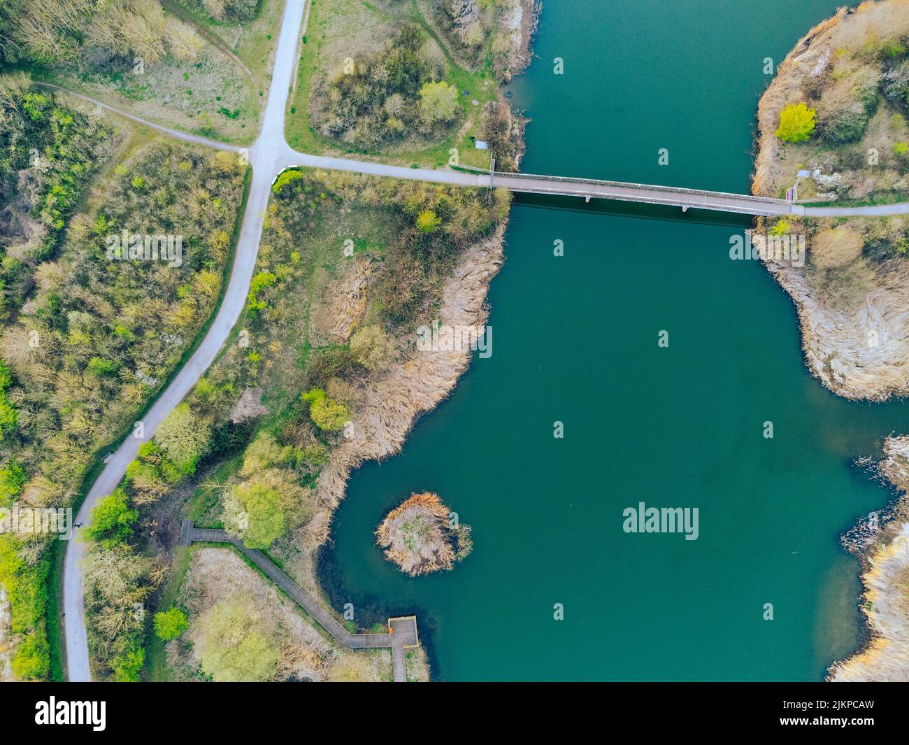 An aerial view of a bridge over a lake connected to an island full of ...