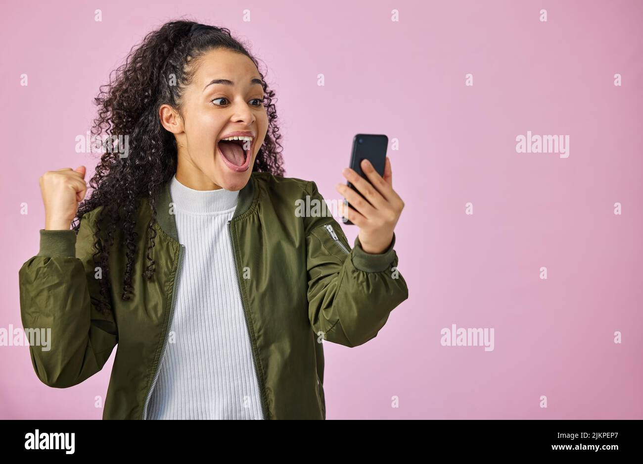 I just won the prize. an attractive young woman standing against a pink ...