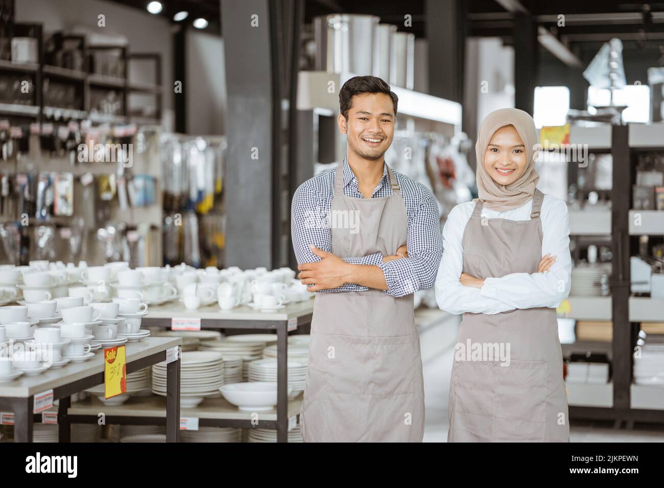 Shop assistant boy and girl in veil with arms crossed Stock Photo - Alamy