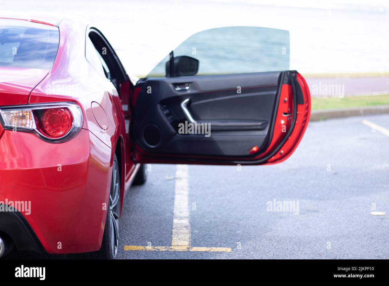 A red sports car with its door open parked on a street Stock Photo - Alamy