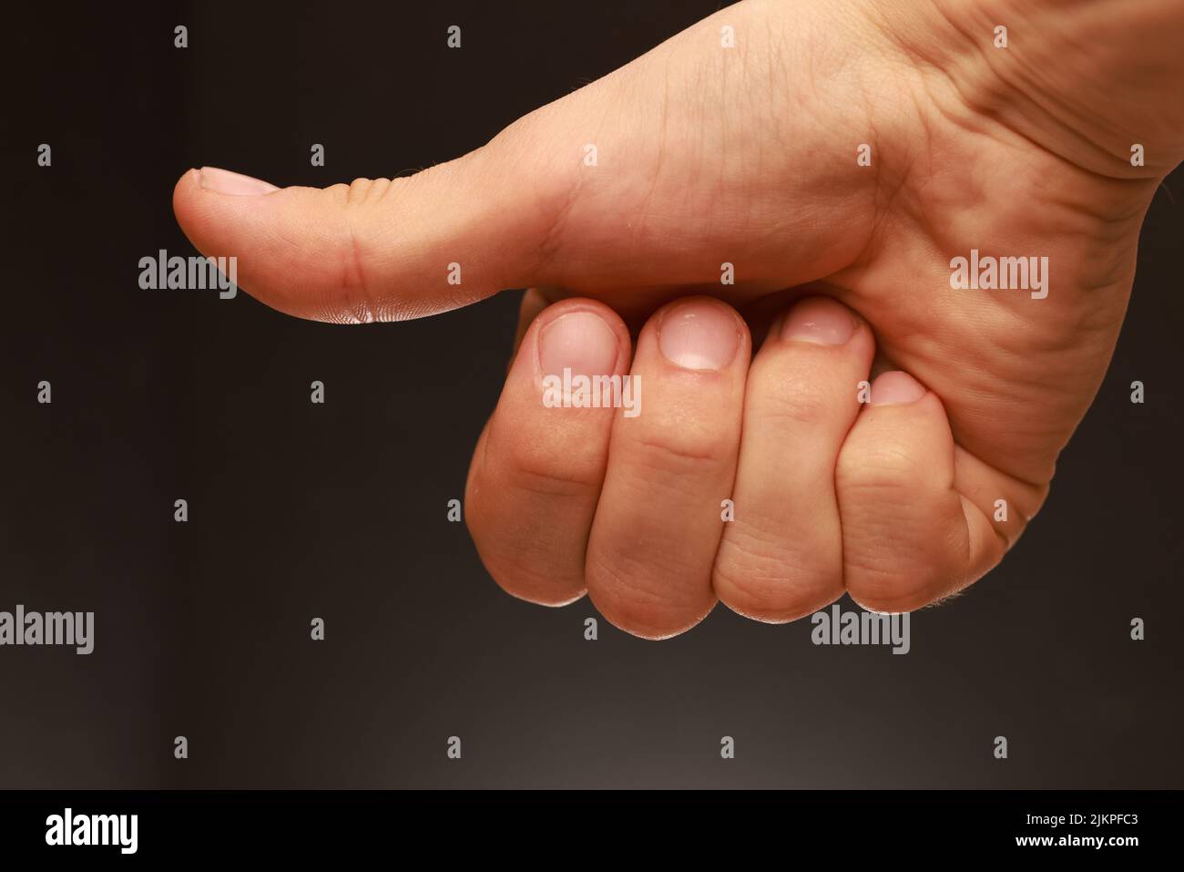A closeup of the fist of a hand with stretched thumb isolated on a ...