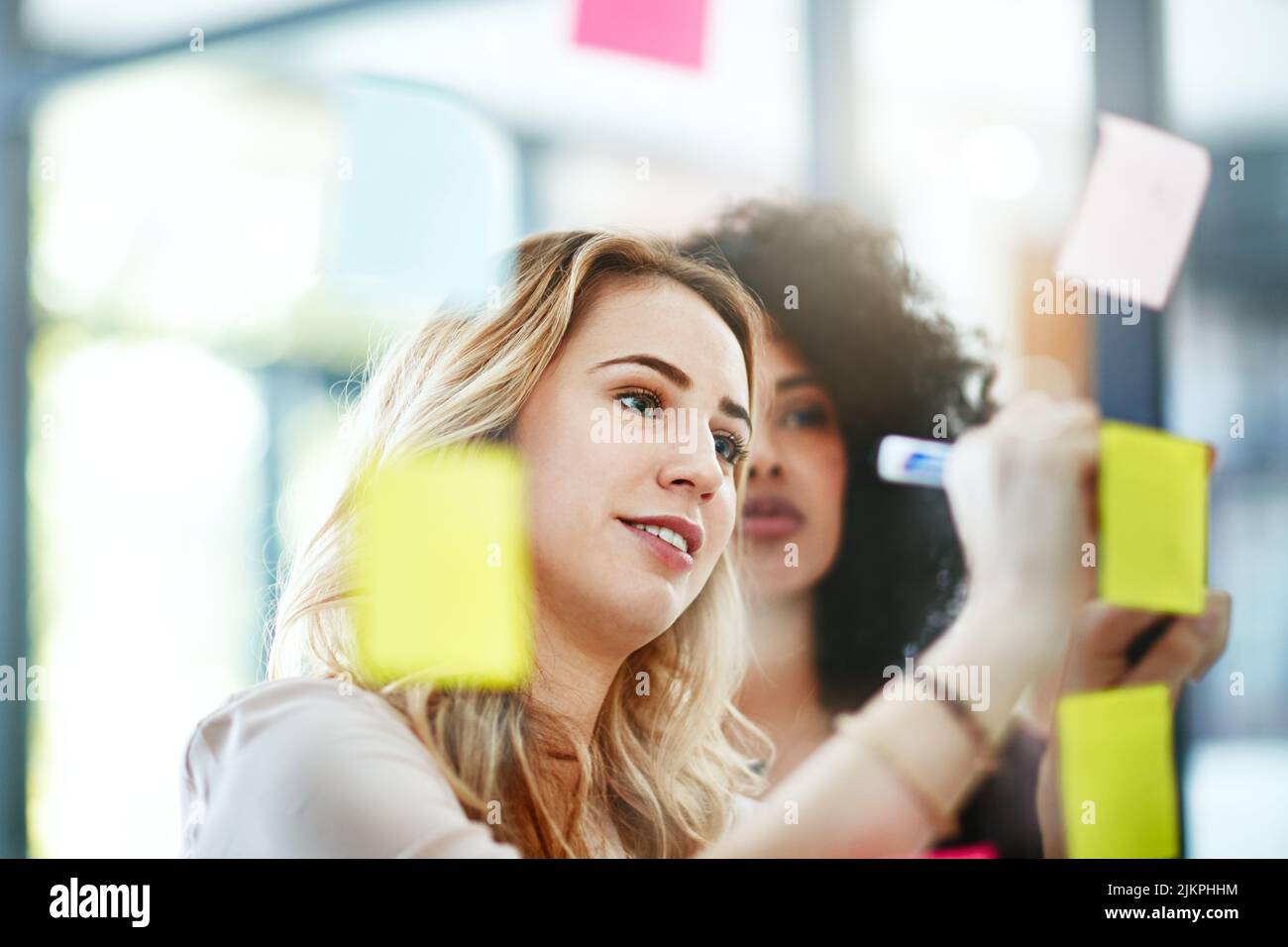 Manager brainstorming, planning and writing sticky notes on glass ...