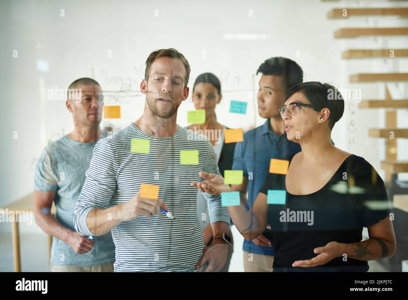 Group of young designers planning on a glass board. A team having a ...
