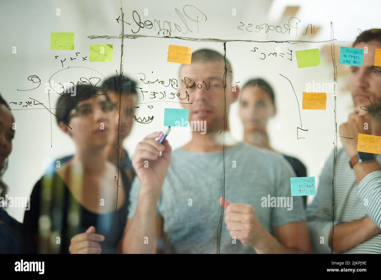 Group of creative business people brainstorm ideas on a glass board ...